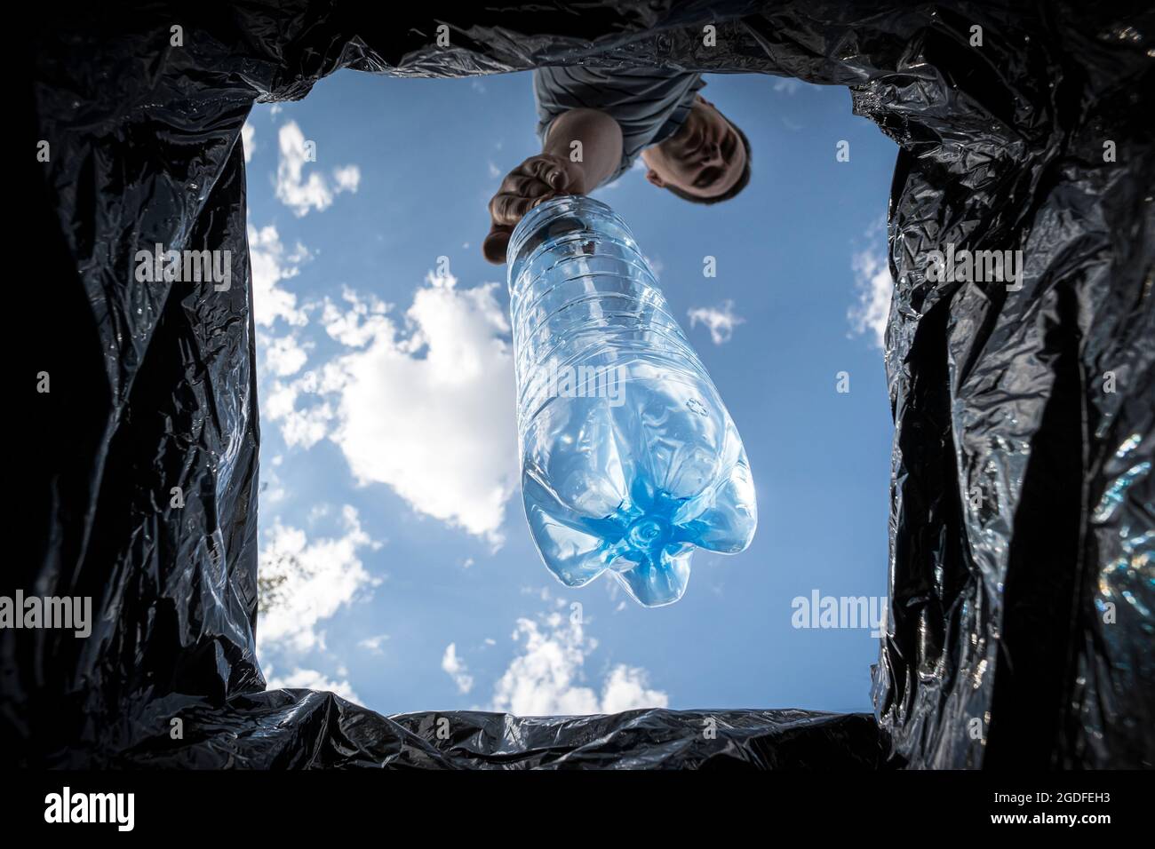 a man throws empty plastic bottle into a trash can. Bottom view from ...