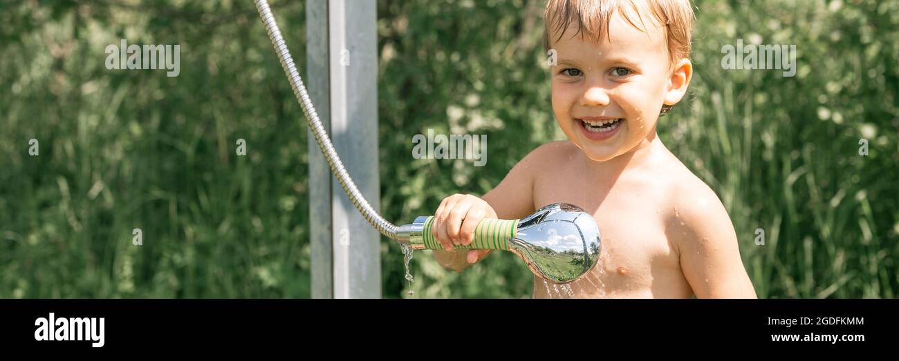 little four year old kid boy fun pours himself with cold water from a ...