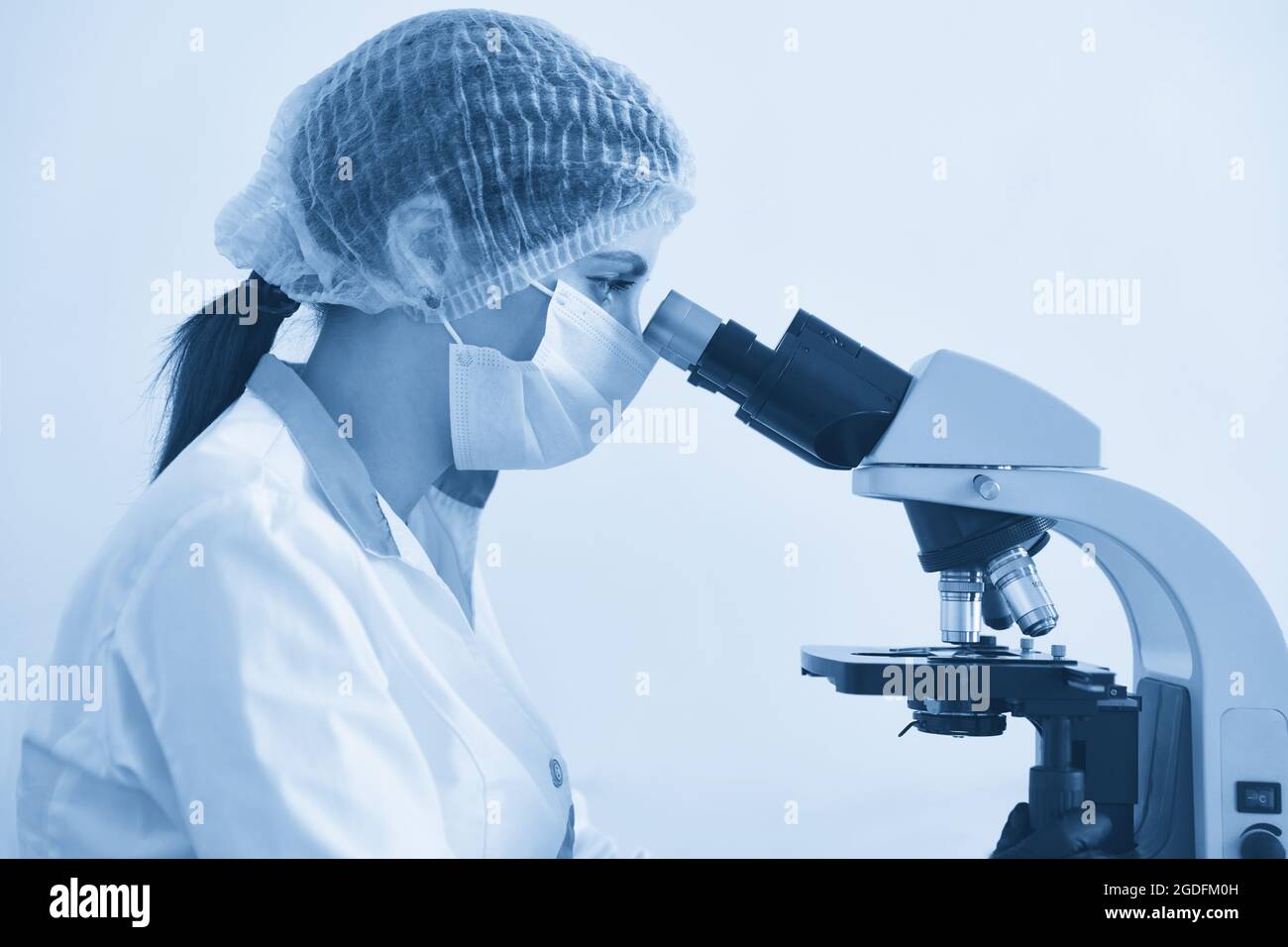 Female scientist looking through microscope in modern chemical ...