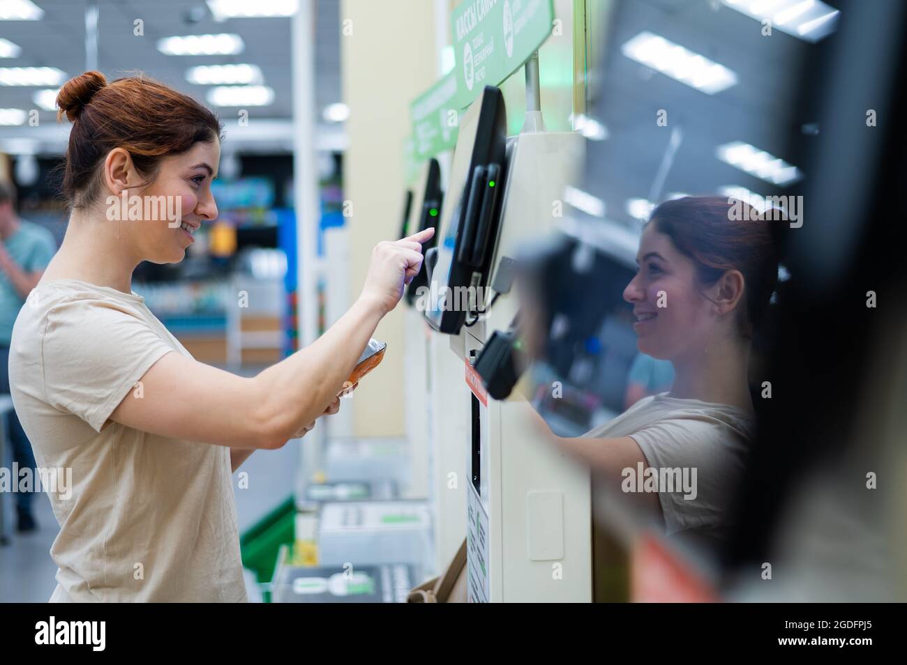 Caucasian woman uses a self-checkout counter. Self-purchase of ...