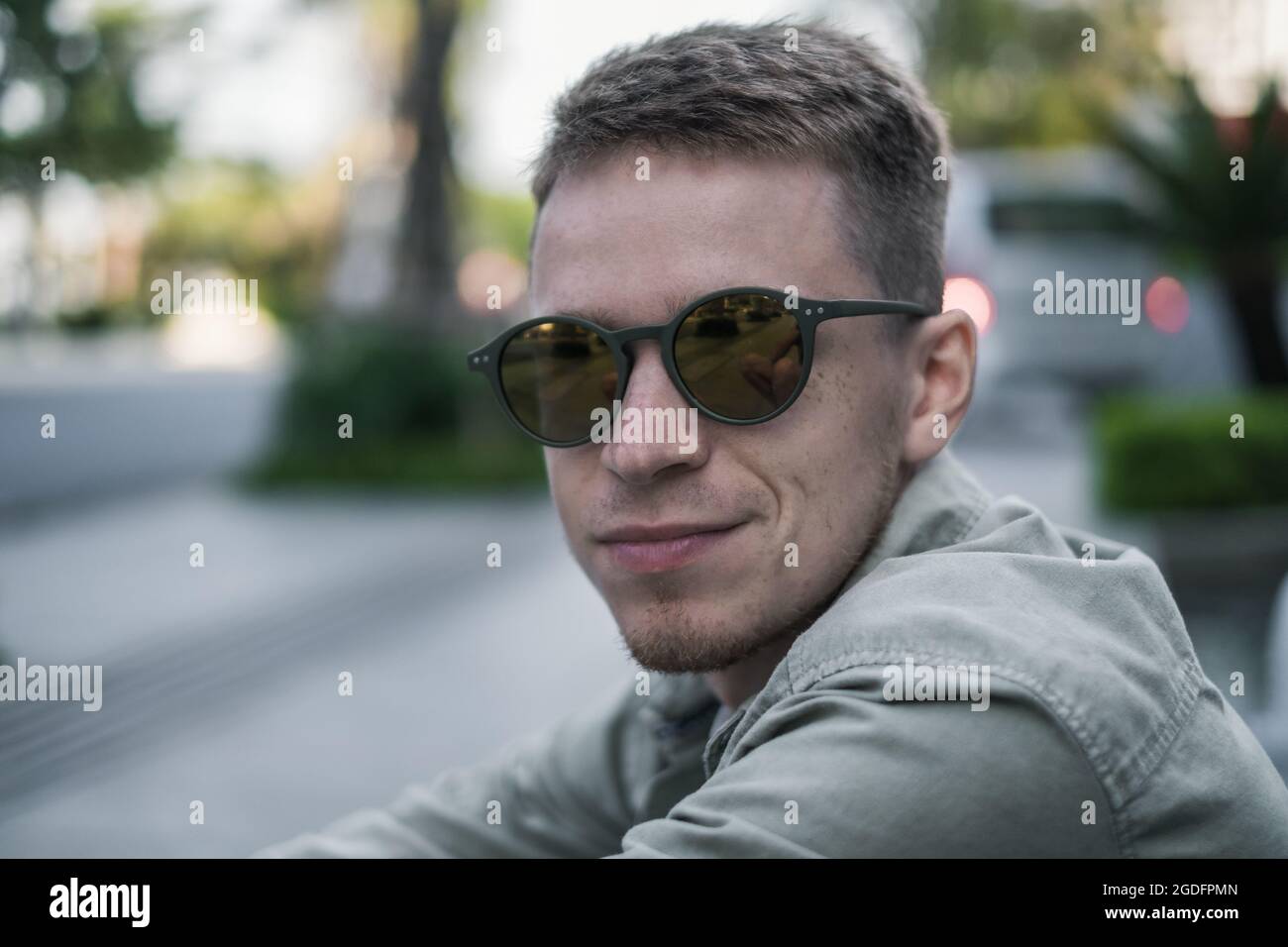 Close up portrait of young man in sunglasses wearing bright-green t ...