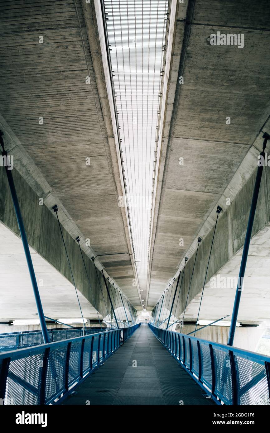 Vertical shot of pedestrian bridge with concrete roof, metal grids and ...