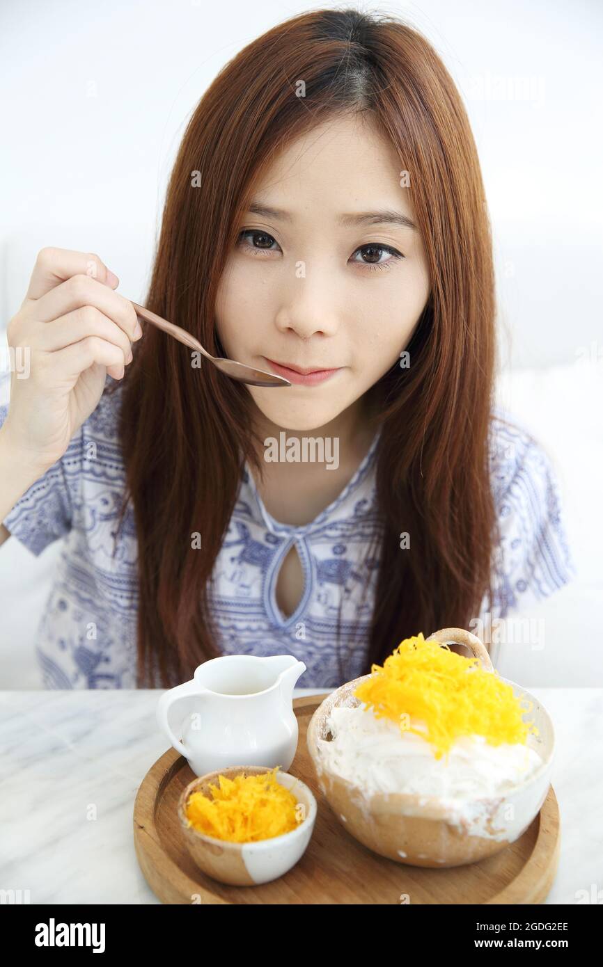 Asian young woman eating Shaved ice with milk and coconut Stock Photo ...