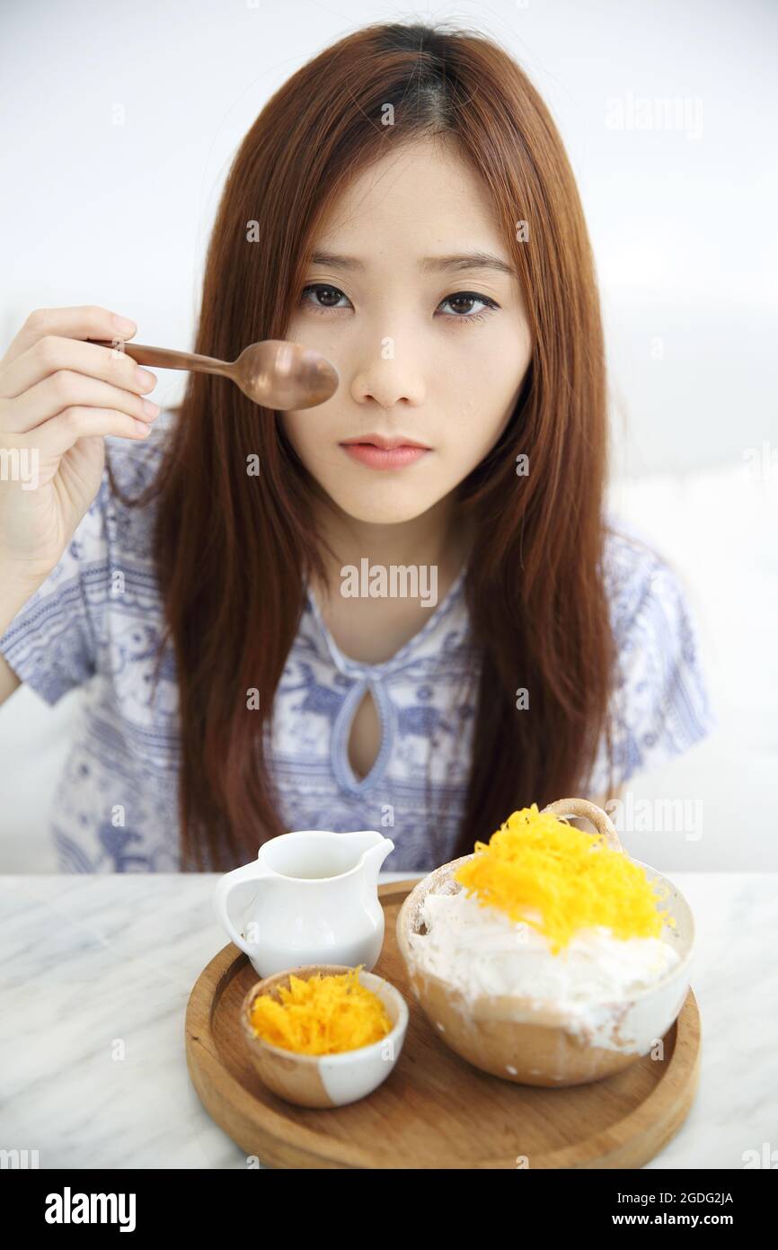 Asian young woman eating Shaved ice with milk and coconut Stock Photo ...