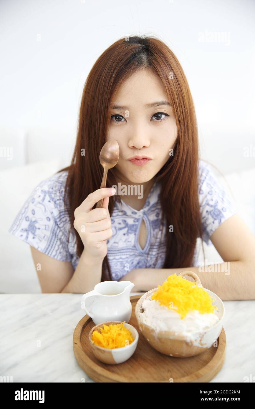 Asian young woman eating Shaved ice with milk and coconut Stock Photo ...