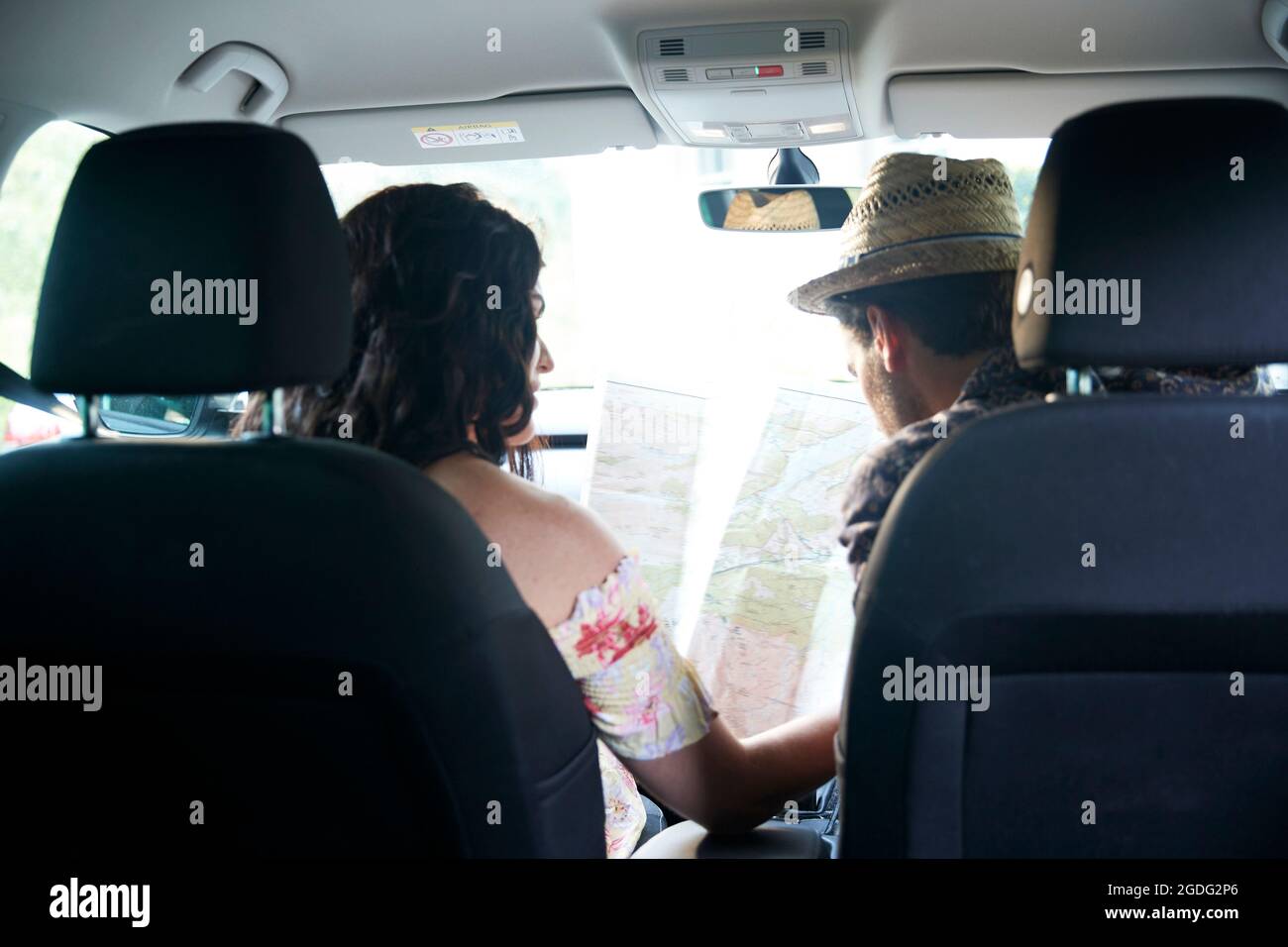 Couple sitting in car looking at folding map, rear view Stock Photo - Alamy