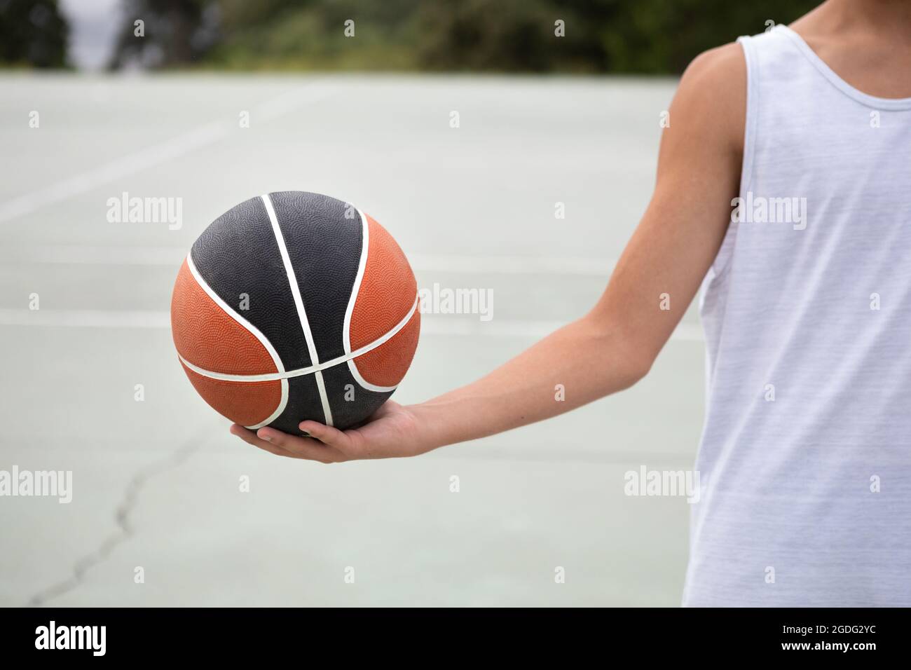 Male teenage basketball player holding ball on basketball court ...