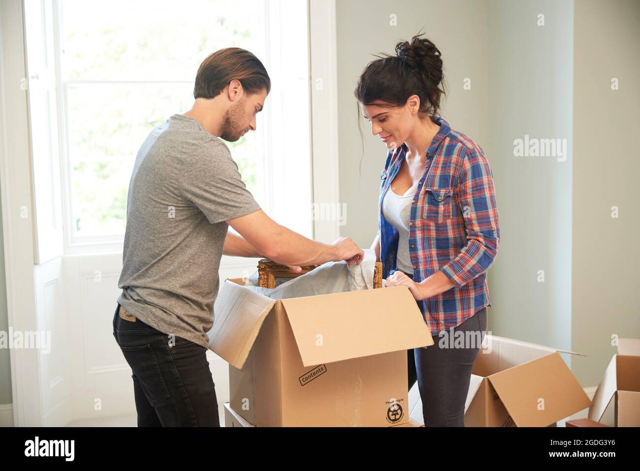 Couple packing mirror into cardboard box Stock Photo - Alamy