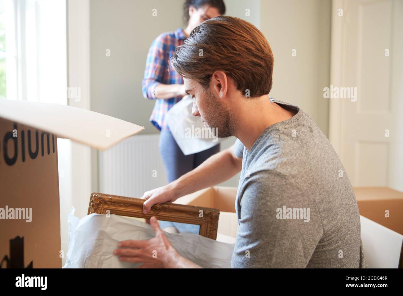 Man packing mirror into cardboard box Stock Photo - Alamy
