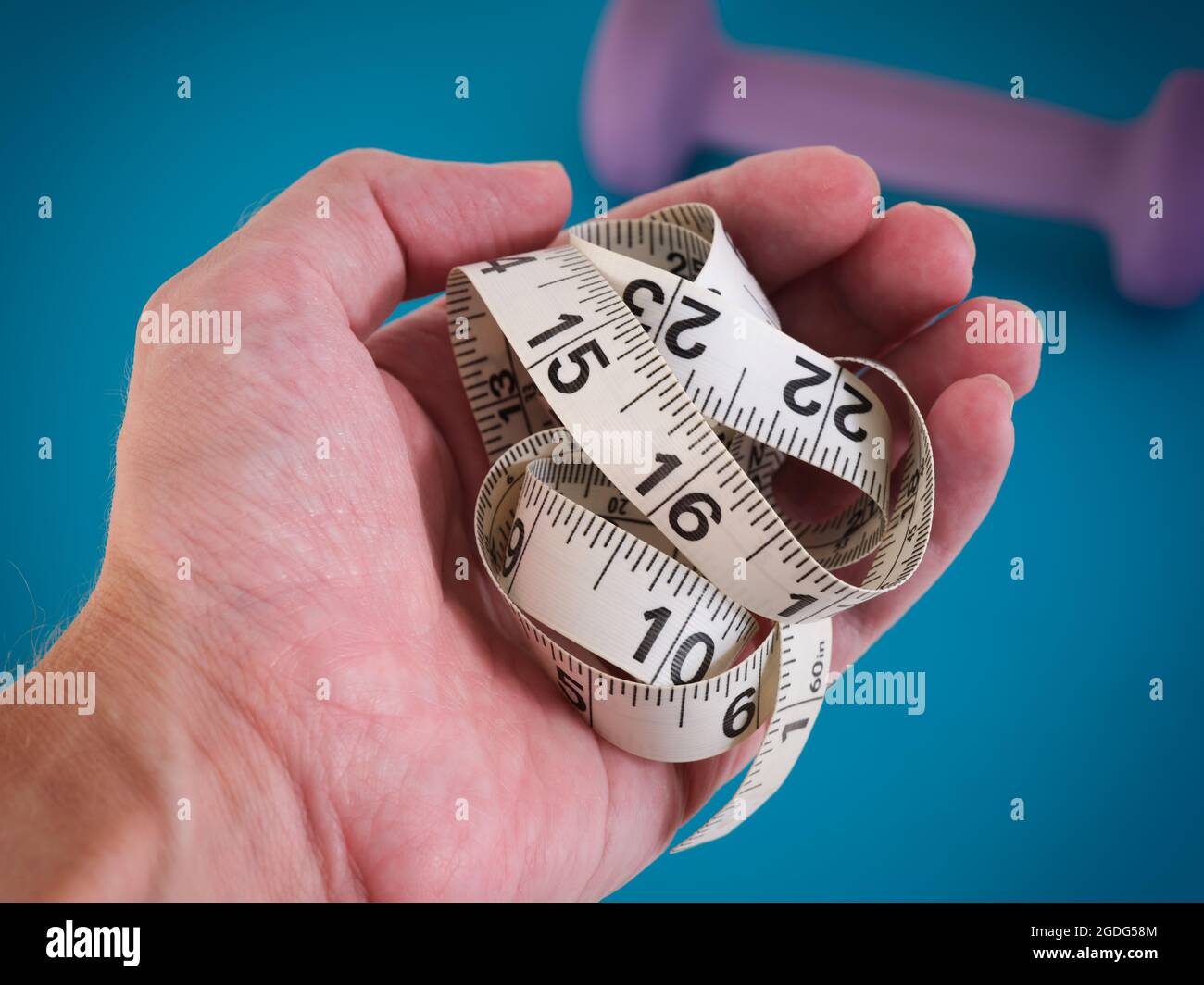 A person holding a tape measure after checking the length of his waist ...