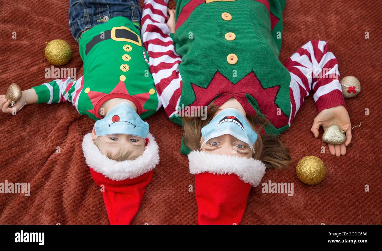 Toddler boy and woman in elf costumes and Santa hats. They have medical ...