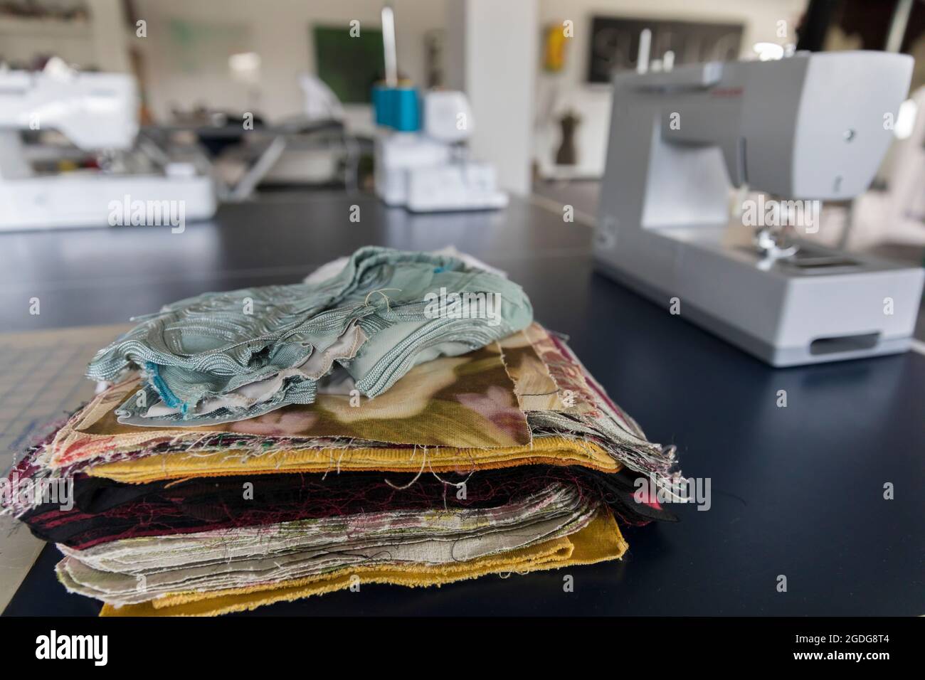 Pile of fabric sample squares with sewing machines in background Stock ...