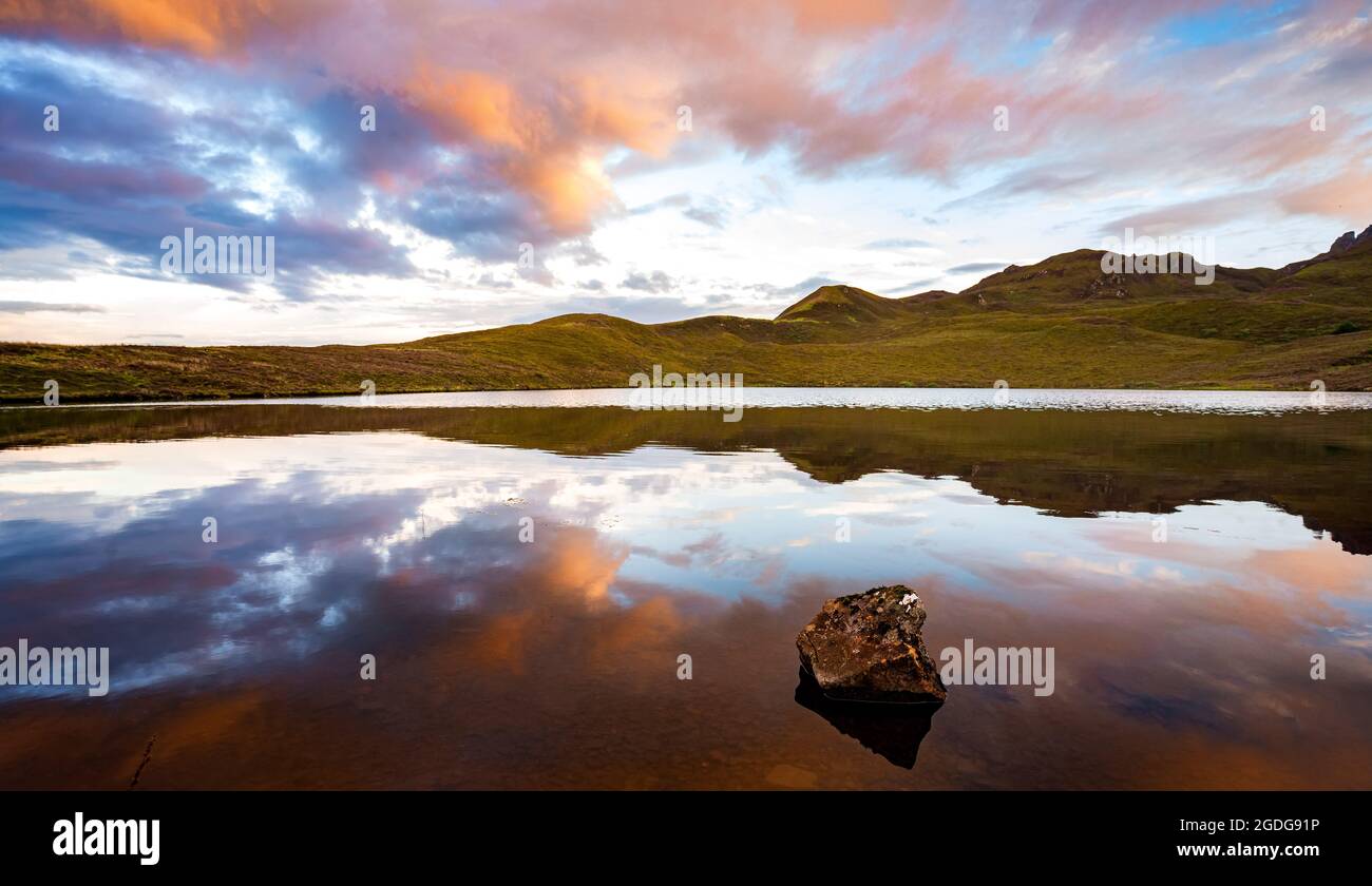 Sunset sky reflection in mirror lake Scotland with heather hills Stock ...