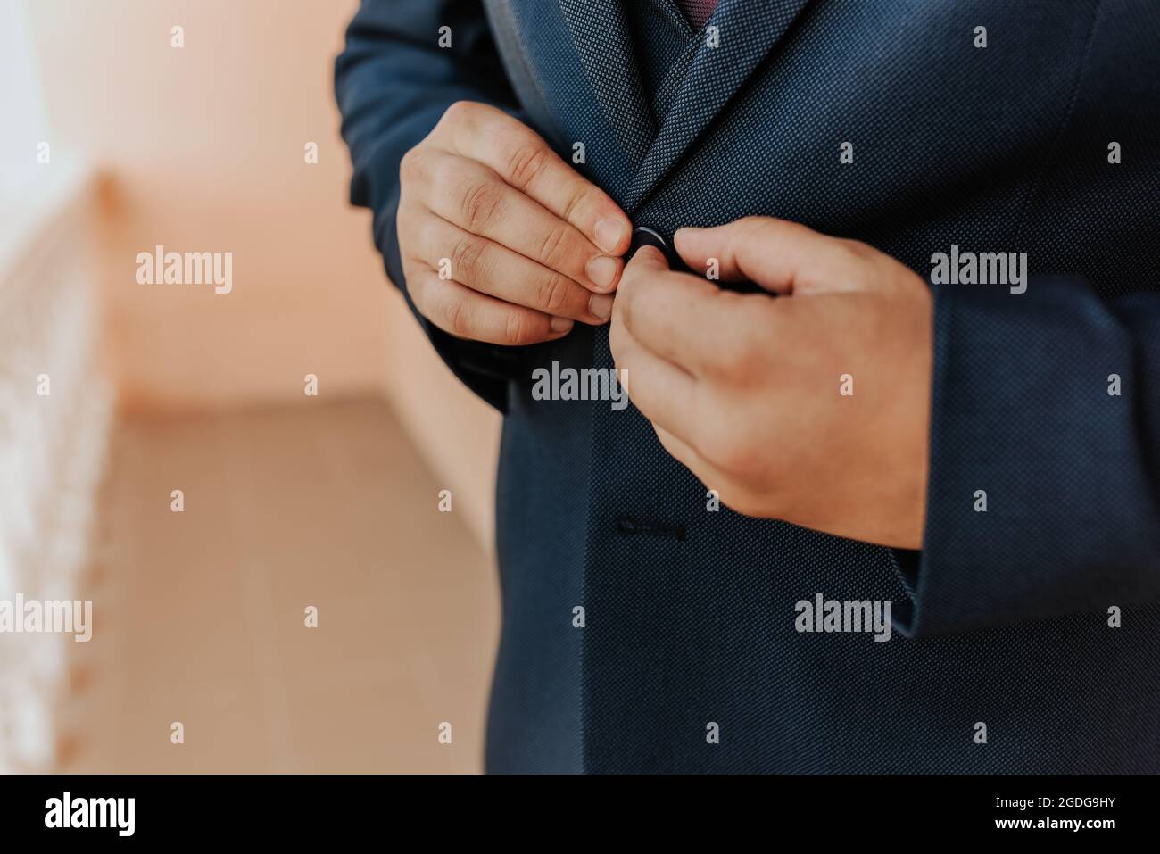 A man in a dark business suit buttoning a button on his jacket. fashion ...