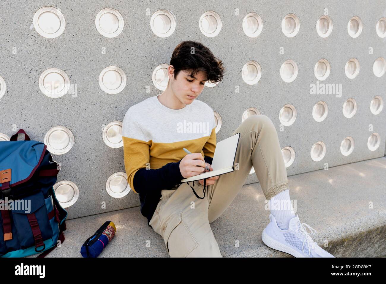 Young male writing notes in a notebook sitting on a bench Stock Photo ...