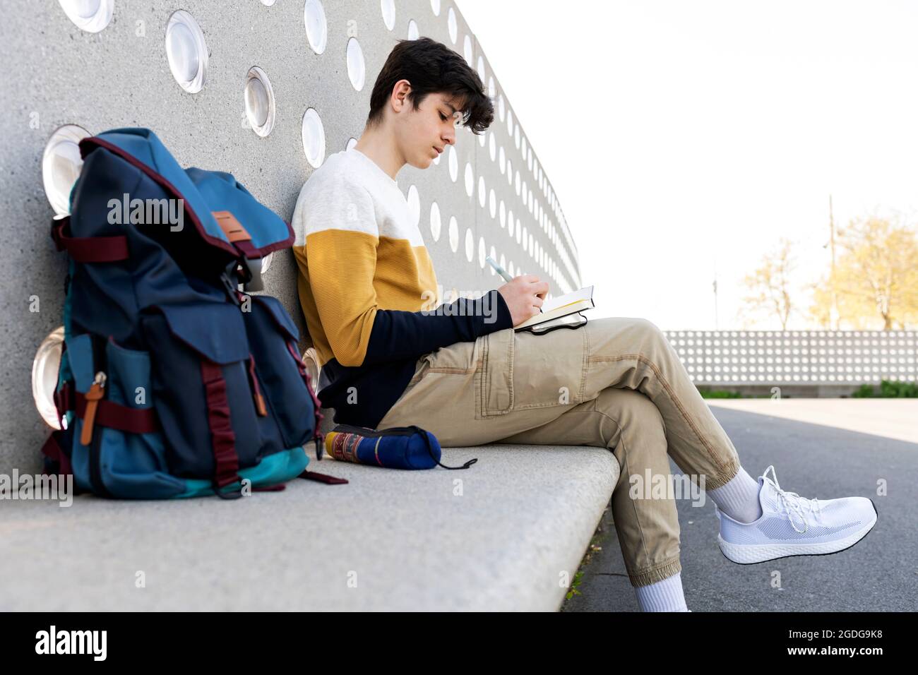 Young male writing notes in a notebook sitting on a bench Stock Photo ...
