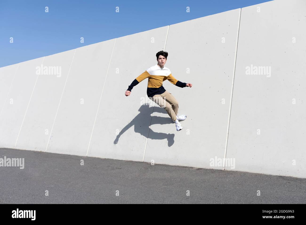 Young man jumping on the urban wall background Stock Photo - Alamy