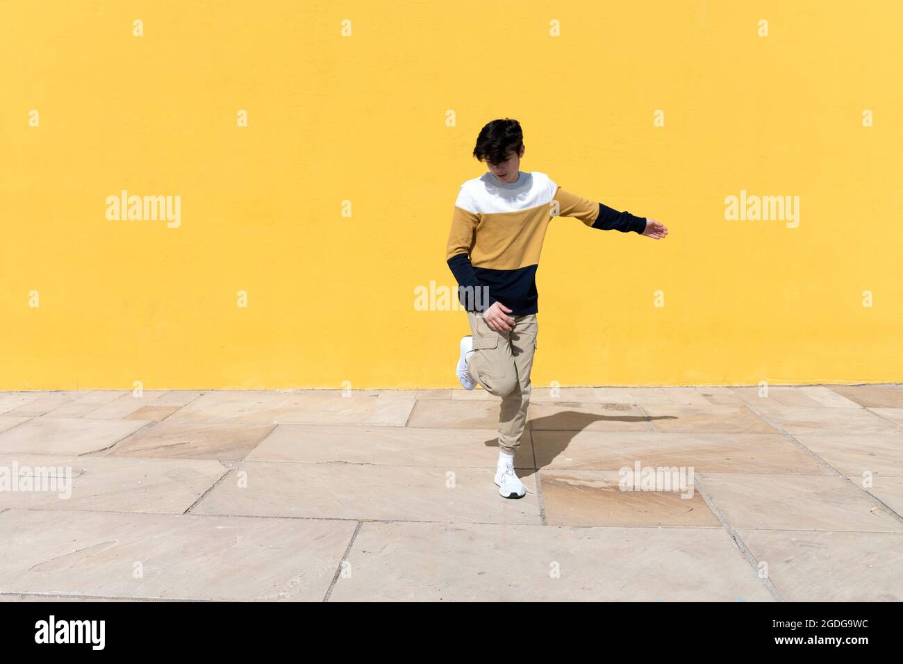 Young man dancing in front of yellow wall Stock Photo - Alamy