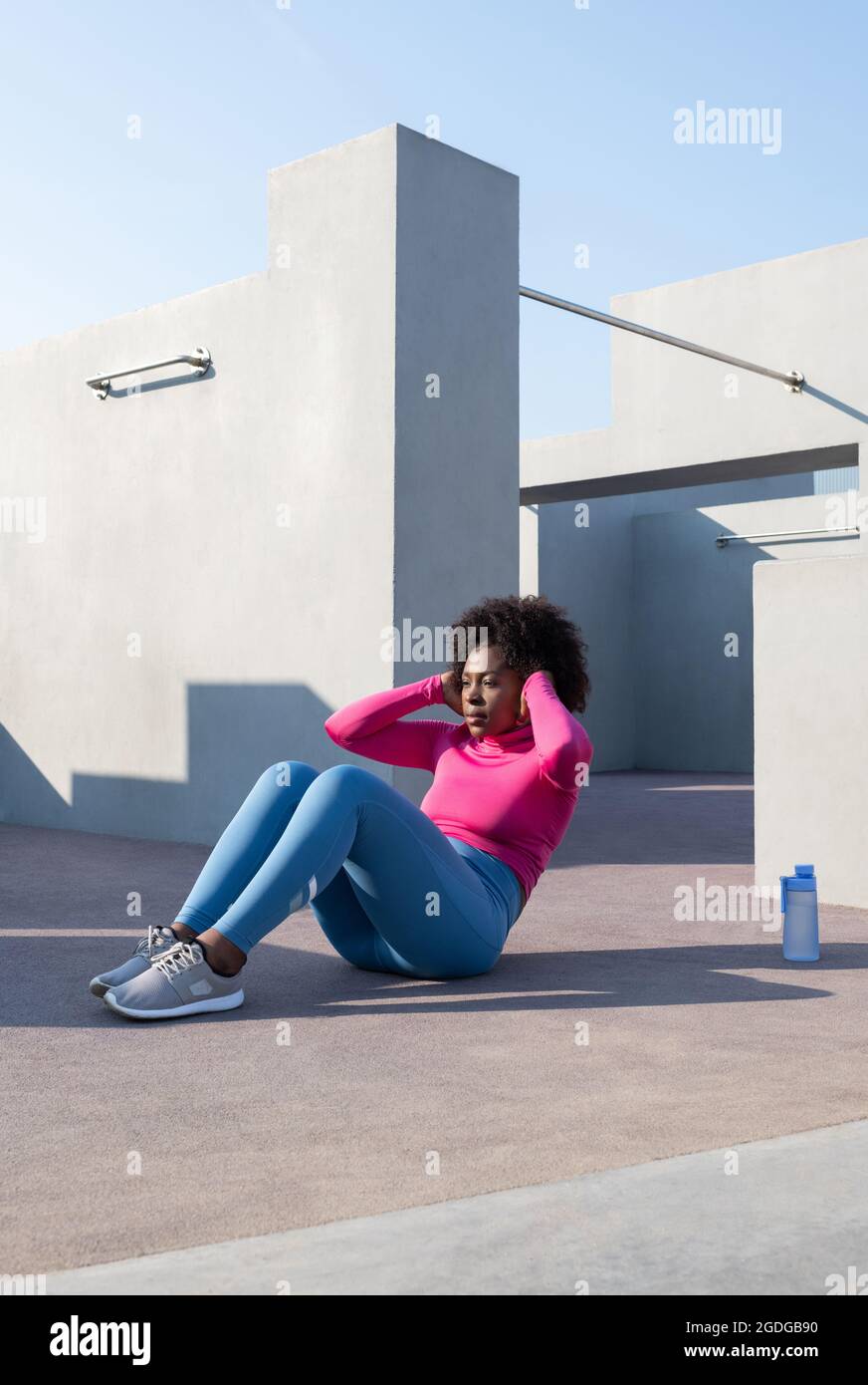 Black sportswoman holding hands behind head and doing abs exercise on ...