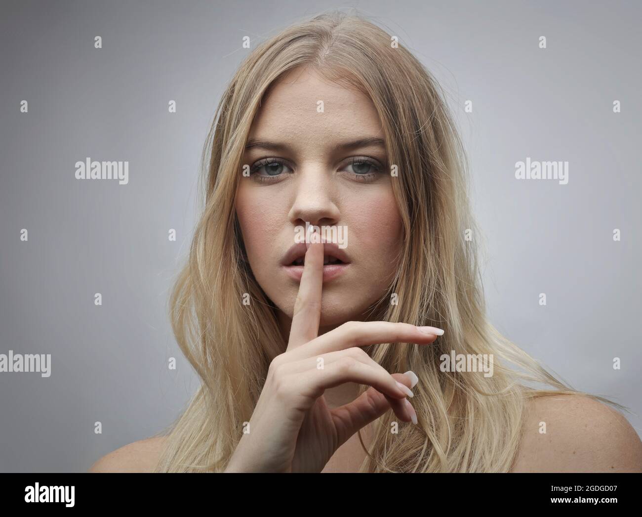portrait of young woman making silence gesture Stock Photo - Alamy