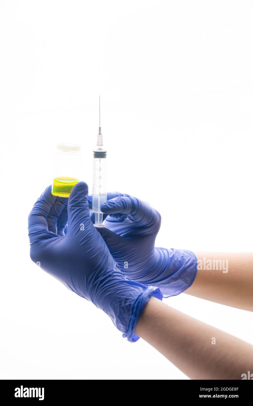Doctor's or nurse hands in medical gloves holding syringe and bottle of ...