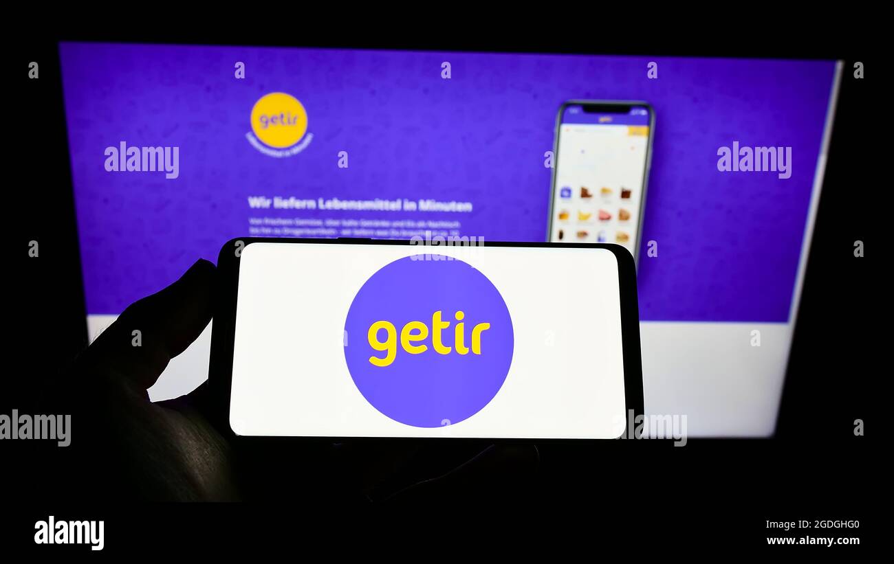 Person holding cellpohone with logo of Turkish delivery company Getir ...