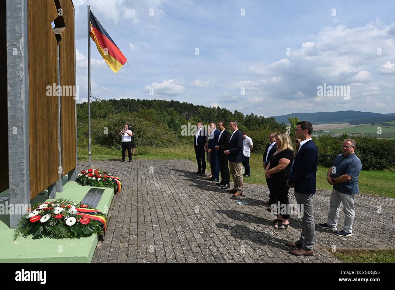 Geisa, Germany. 13th Aug, 2021. Participants stand in front of wreaths ...