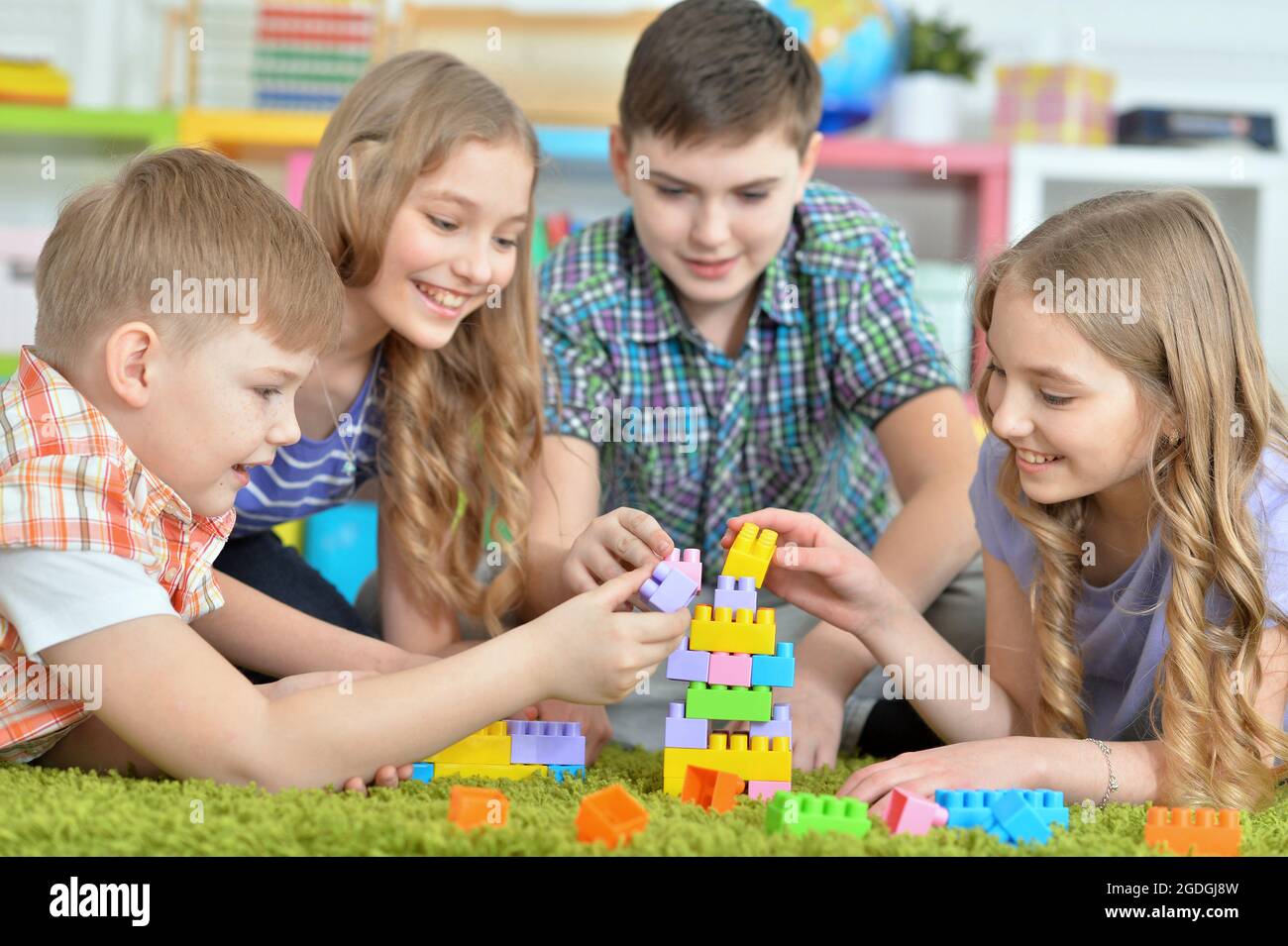 Children playing together floor with green carpet Stock Photo - Alamy