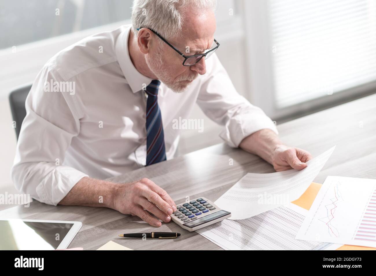 Businessman doing his accounting with calculator Stock Photo - Alamy