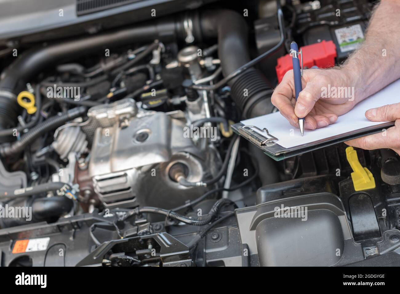 Car mechanic checking a car engine and writing on clipboard Stock Photo ...
