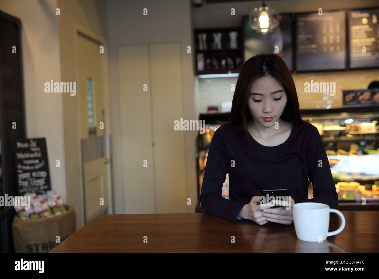 Asian female with hands typing text message and coffee Stock Photo - Alamy