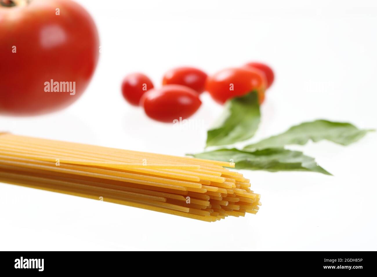 Raw spaghetti noodle with tomatoes and basil isolated in white ...