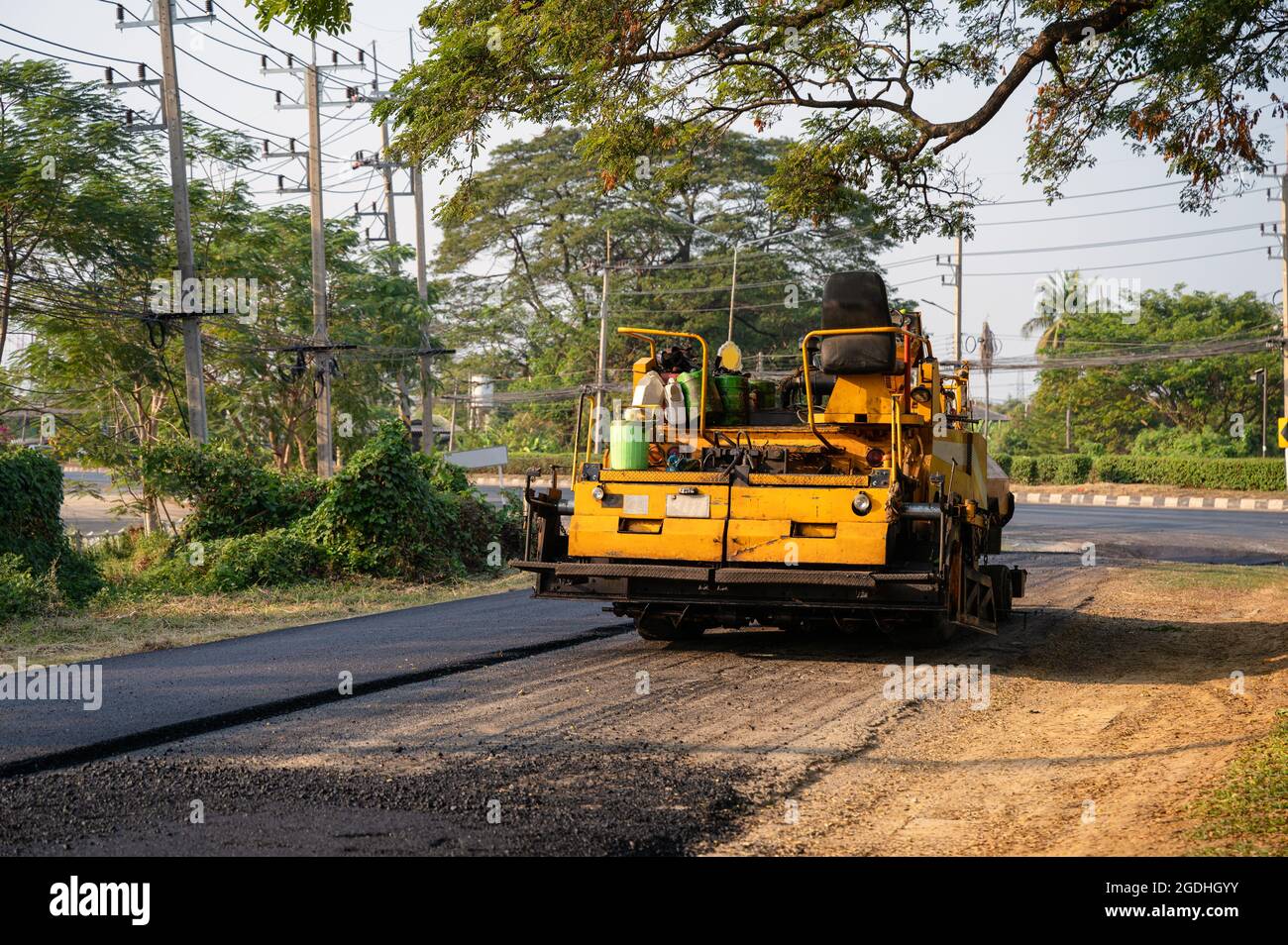 Yellow steamroller or soil compactor working on asphalt highway road at ...