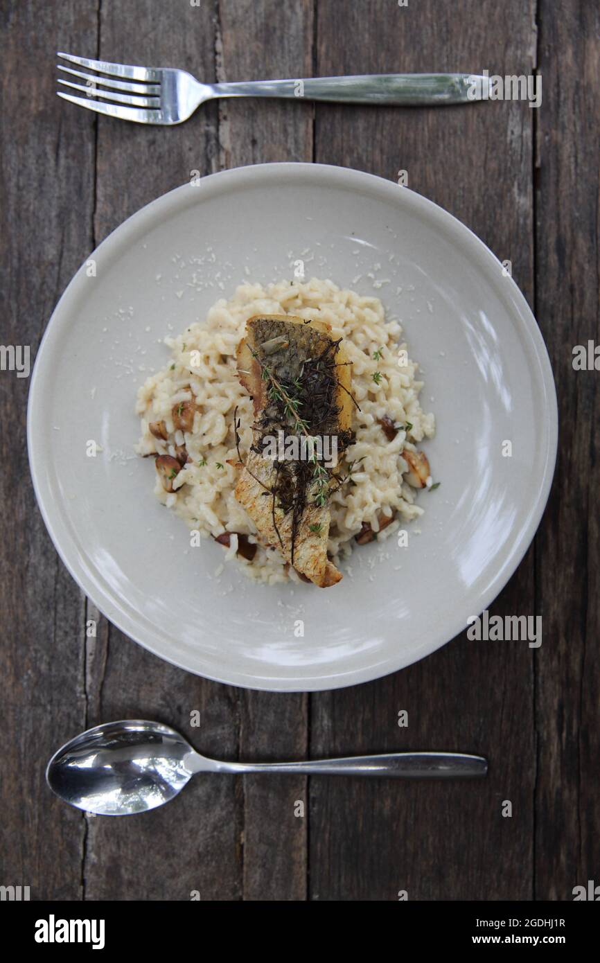 risotto with sea bass fillet steak on wood background , italian food ...