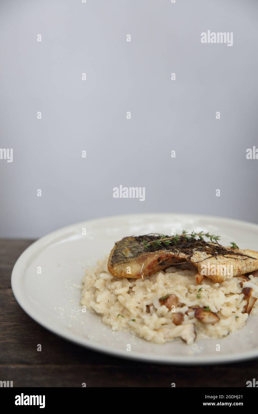 risotto with sea bass fillet steak on wood background , italian food ...