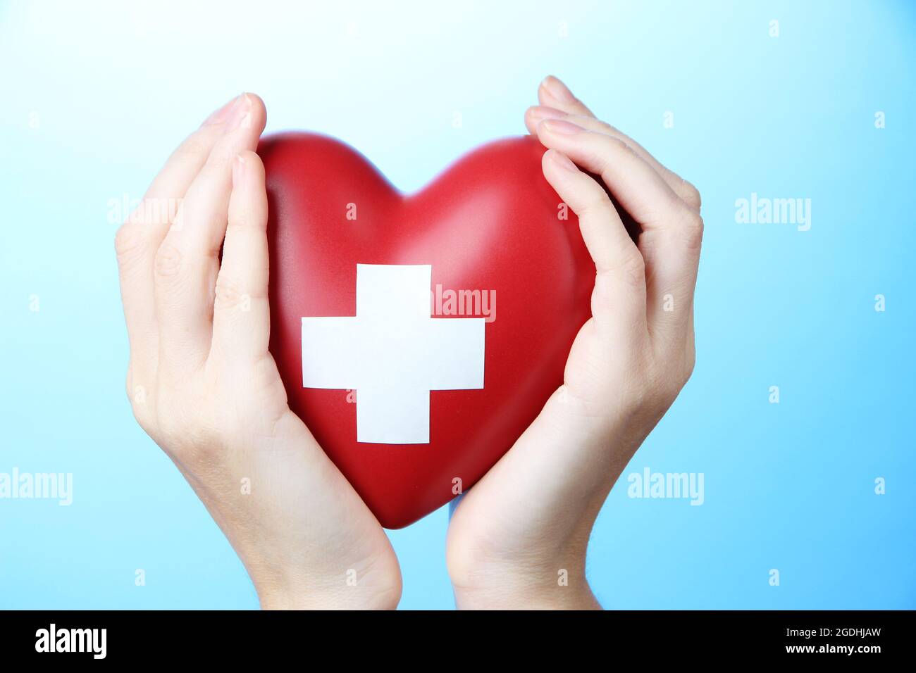 Red heart with cross sign in female hand, close-up, on color background ...