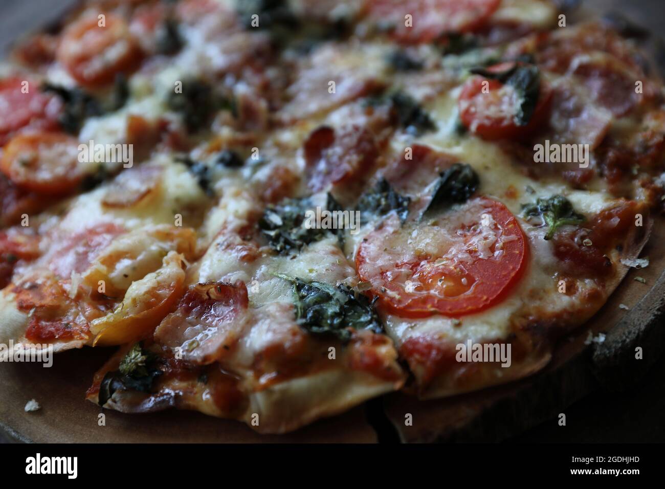 Pizza bacon ham tomato and cheese on top on wood background vintage ...