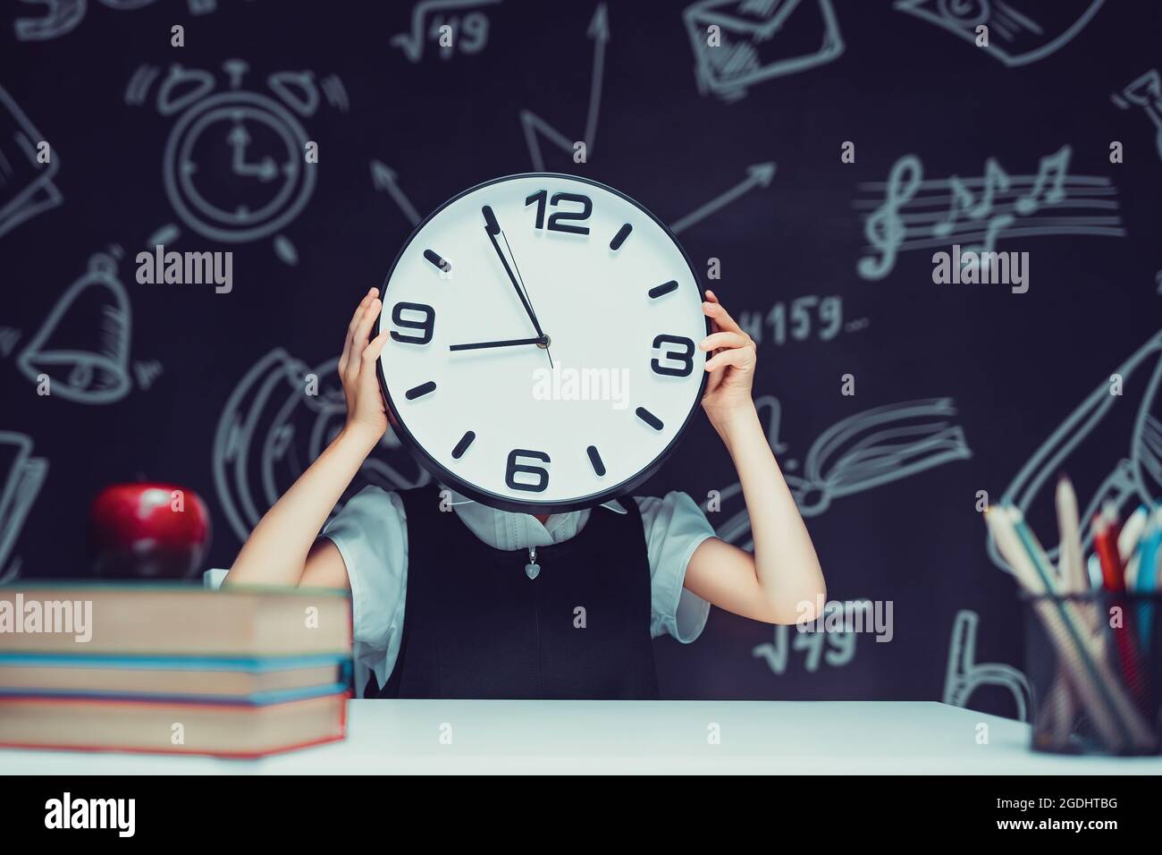 Teenager girl holds a big clock in her hands, watch covers her face ...