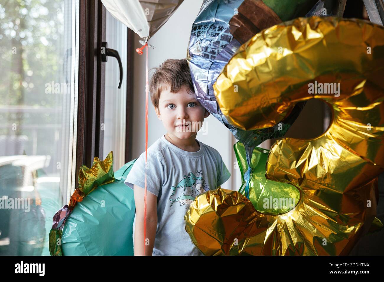 Cheerful birthday boy stands near the window Stock Photo - Alamy