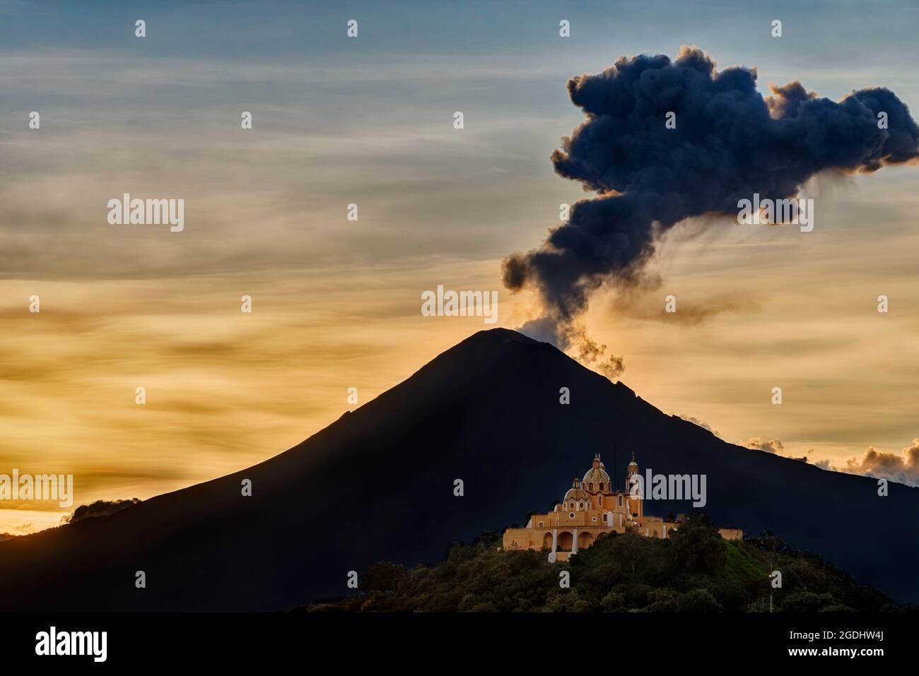 A church on top of a hill with an active volcano behind Stock Photo - Alamy