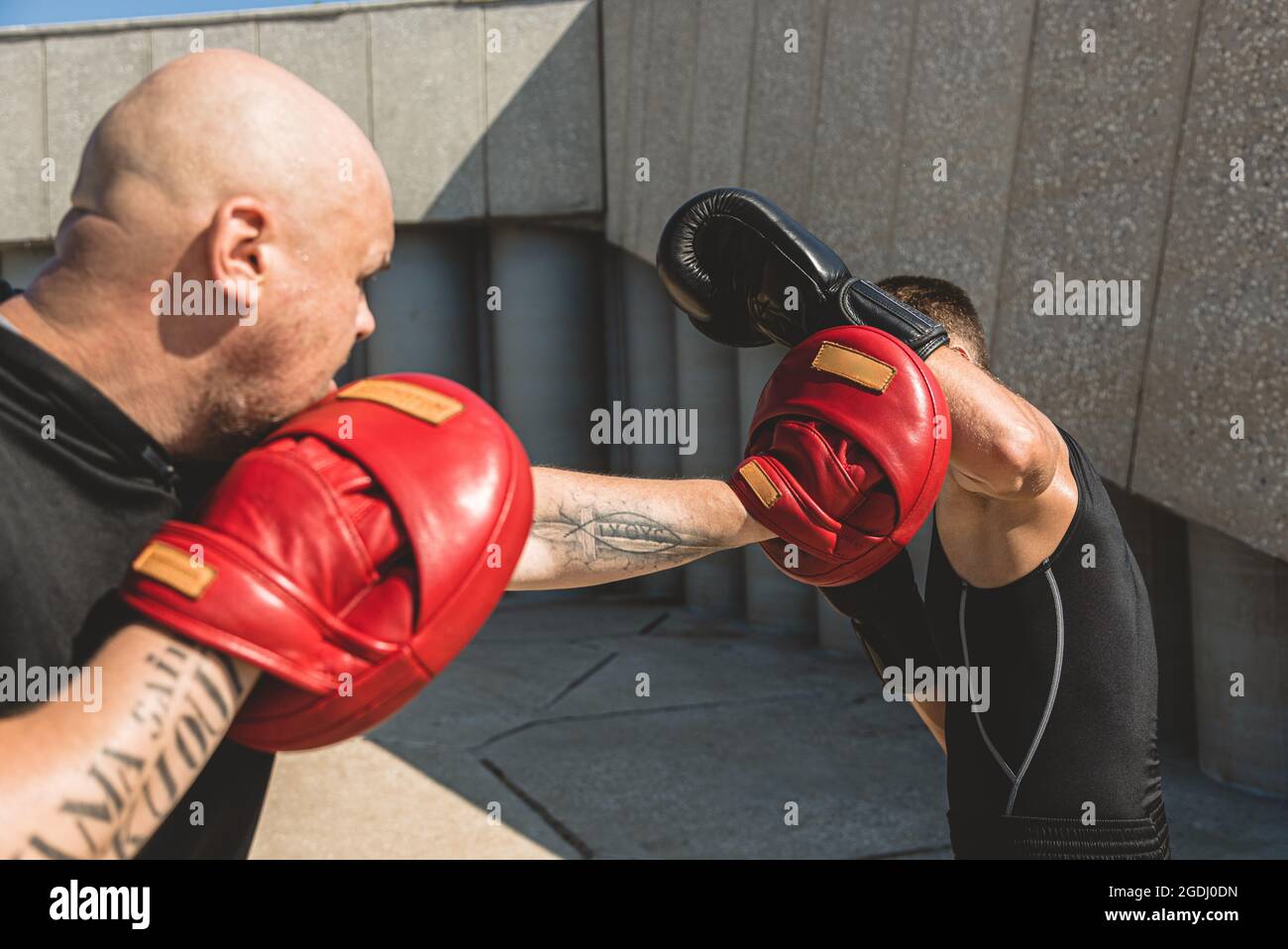 Two men exercising and fighting in outside. Boxer in gloves is training ...