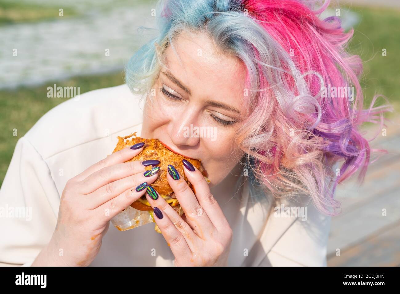 Caucasian woman with curly colored hair eating burger. Bad eating ...