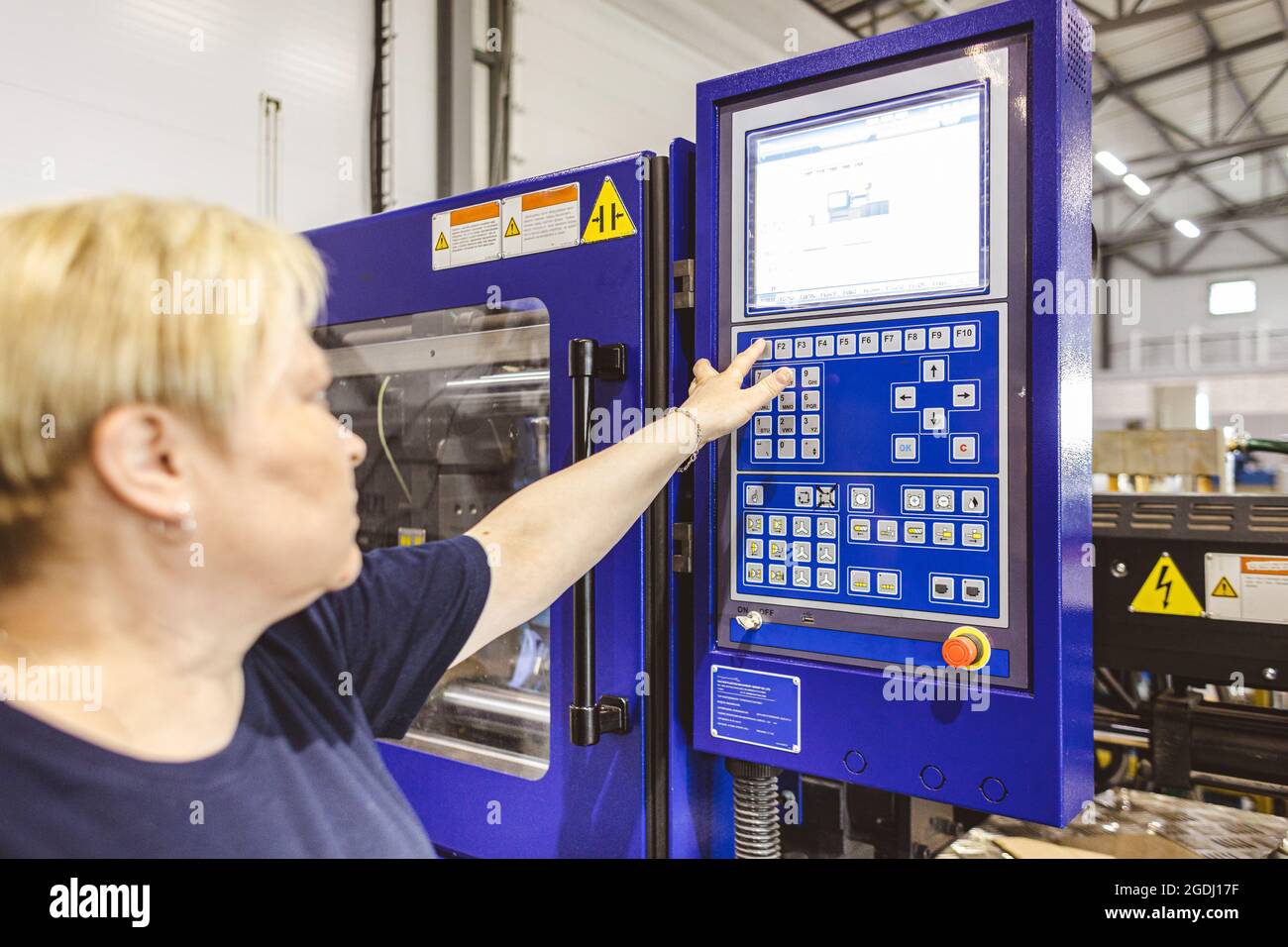 A worker woman presses a button and starts an automatic manufacturing ...