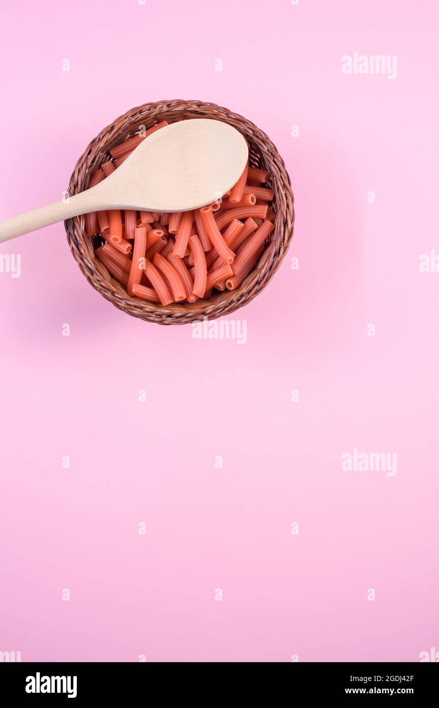 Vertical shot of macaroni with a spoon on a light pink background Stock ...