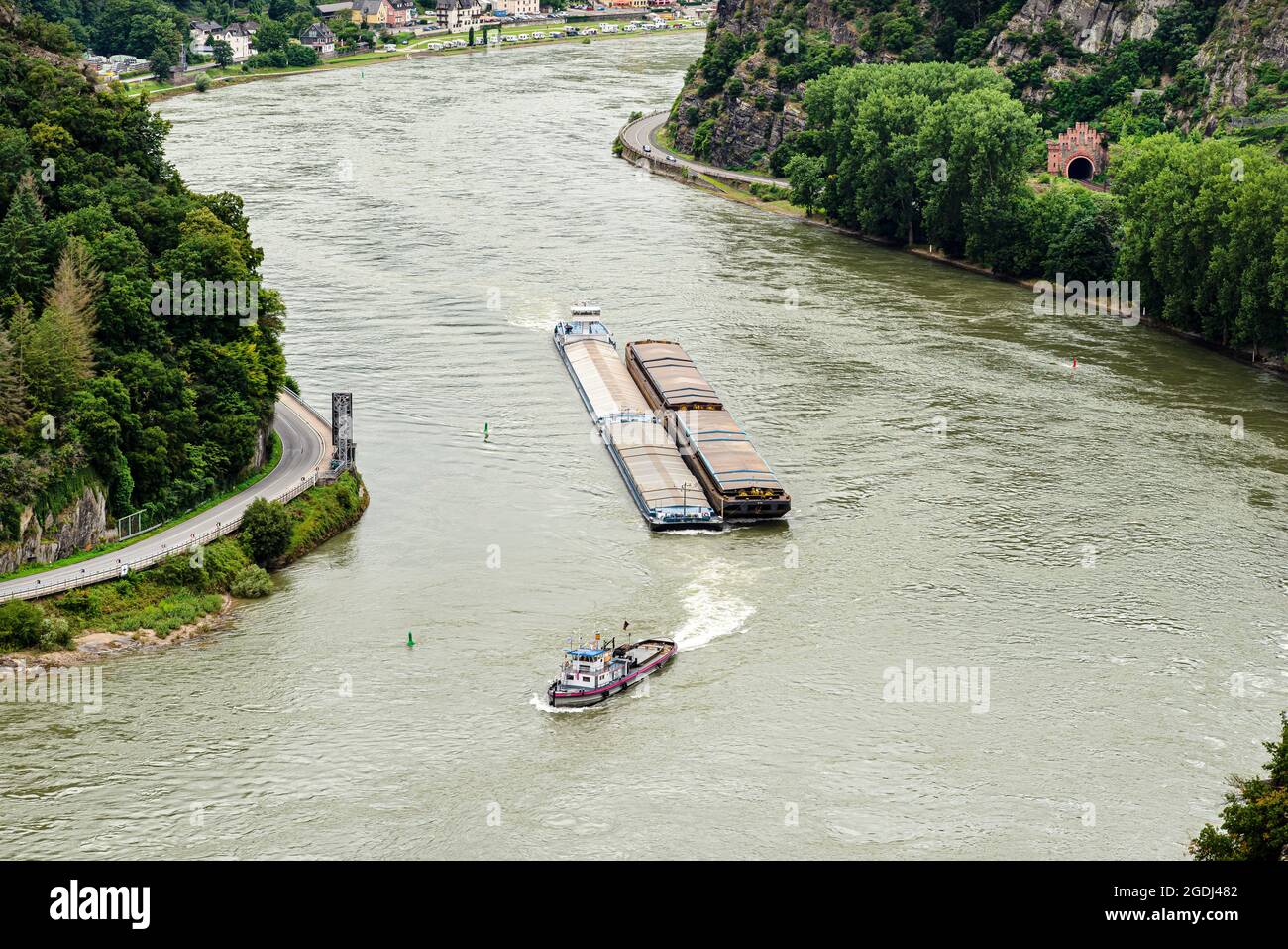 Two barges with a covered deck led by a tugboat on the Rhine river in ...