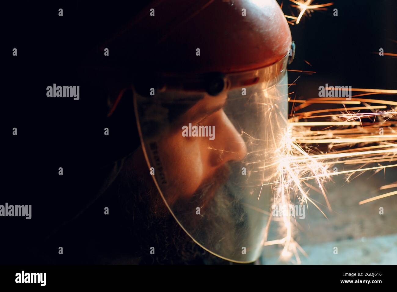 Man worker in transparent protective mask works on metal with circular ...