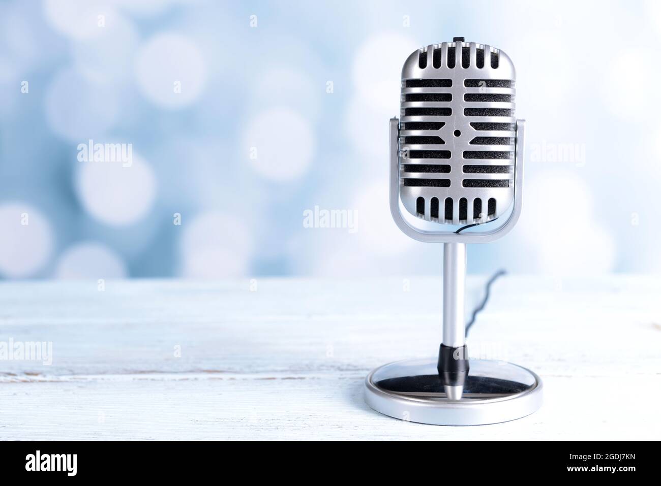 Vintage microphone on table on light blue background Stock Photo - Alamy