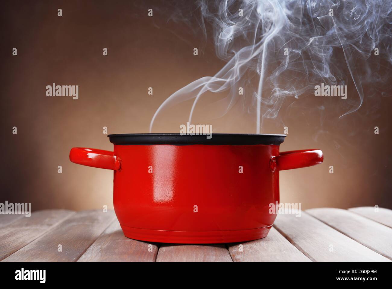 Cooking pot with steam on table on brown background Stock Photo - Alamy