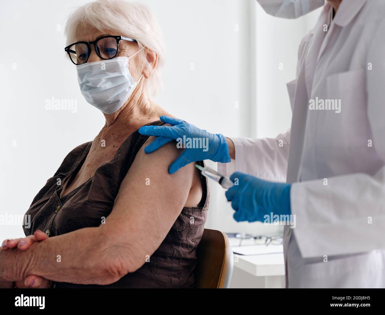 Nurse giving an injection to an elderly woman patient immunity ...