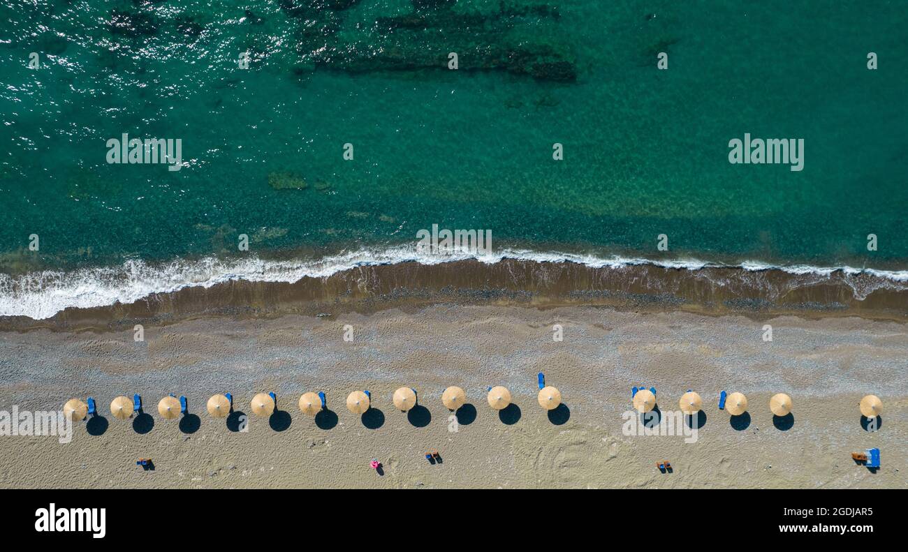 Aerial view from a flying drone of beach umbrellas in a row on an empty ...